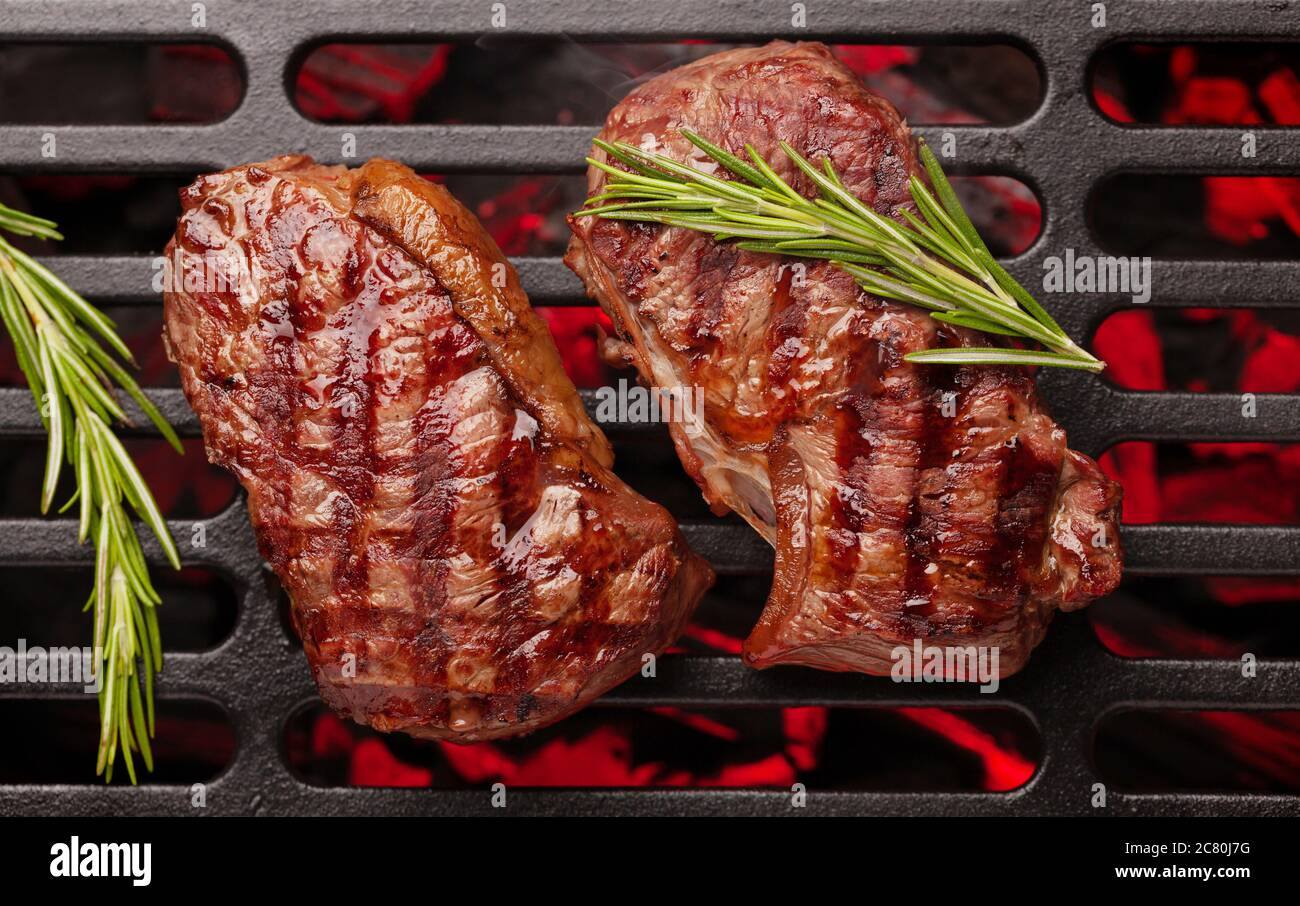 Beef steaks cooking on grill with spices and herbs. Top view flat lay ...