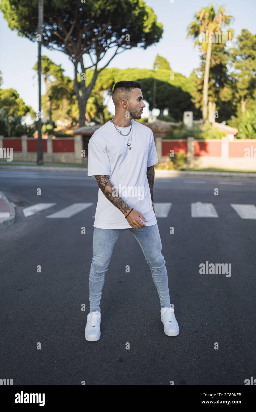 Vertical shot of a Caucasian male with tattoos wearing fashionable ...