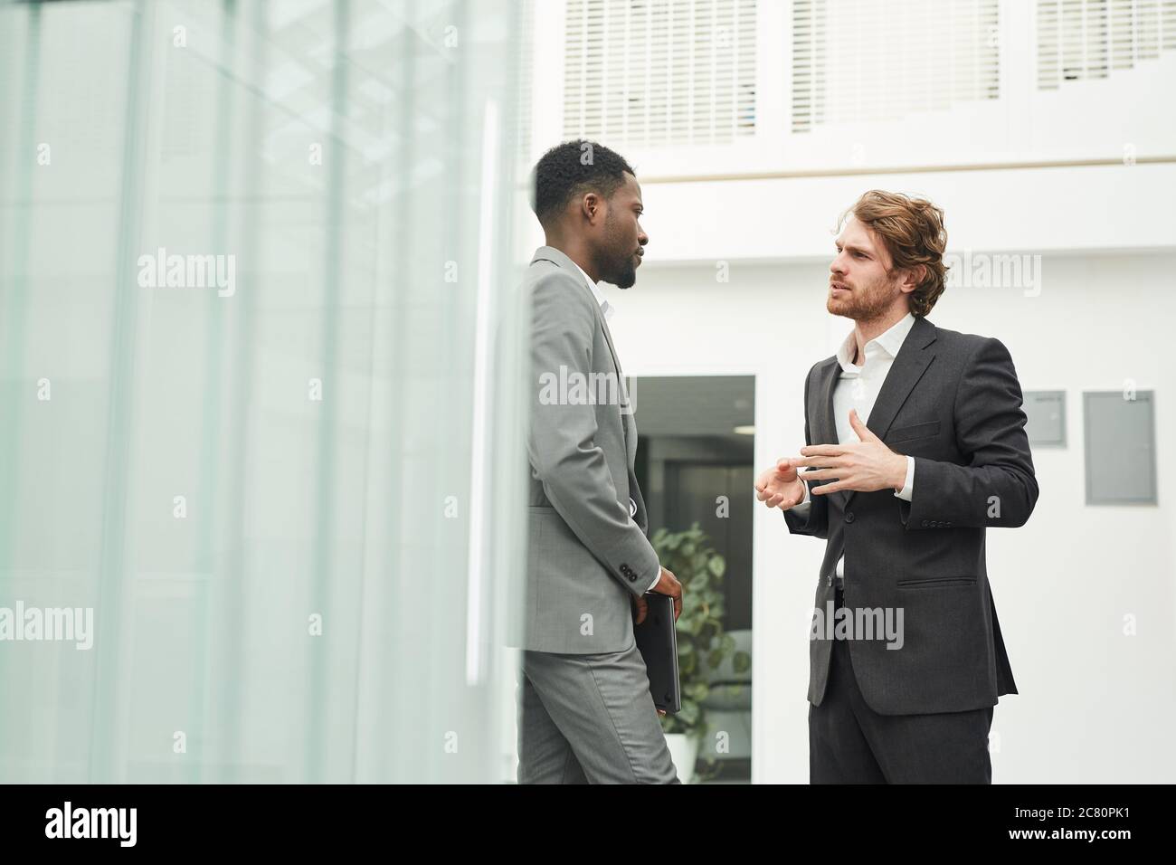 Portrait of two successful businessmen wearing suits chatting while ...