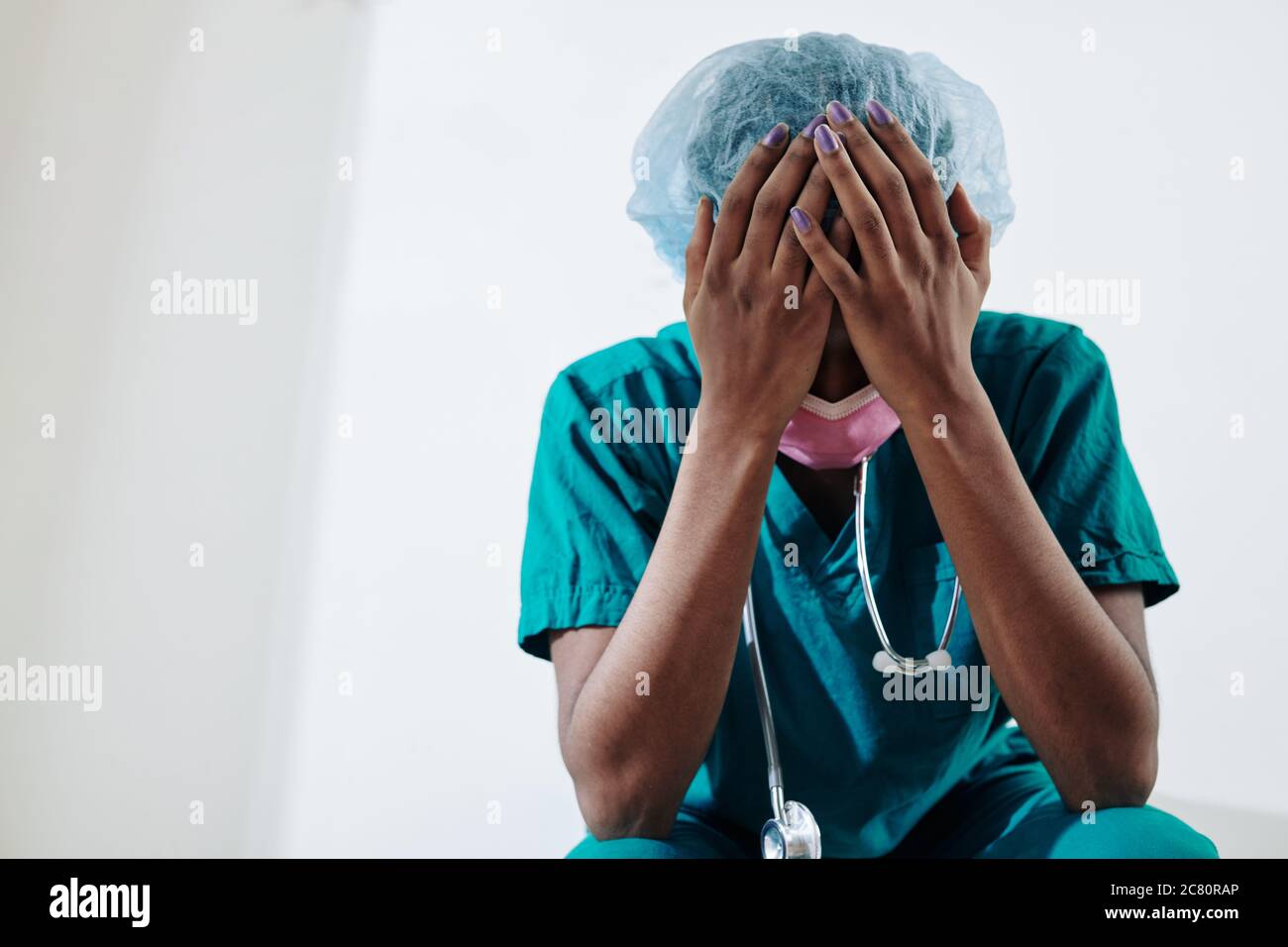 Crying nurse covering her face with hands, she is tired of working ...