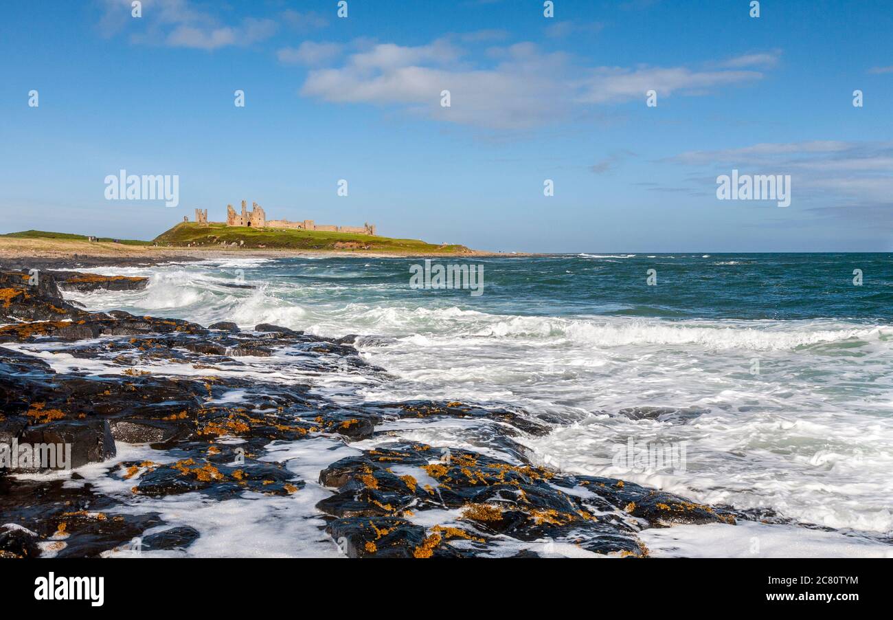 Waves breaking on the black igneous rocks at Dunstanburgh Castle ...