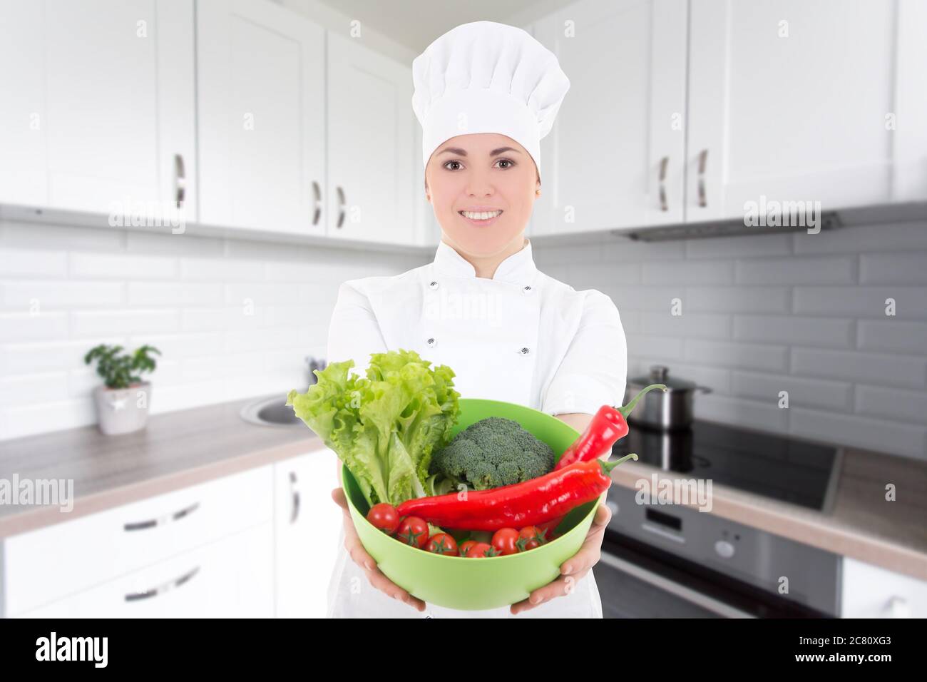 young attractive cook woman in uniform with vegetarian food in modern ...