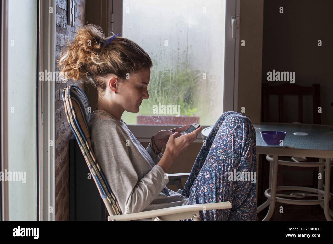 Caucasian female sitting on a chair while texting on her phone Stock ...