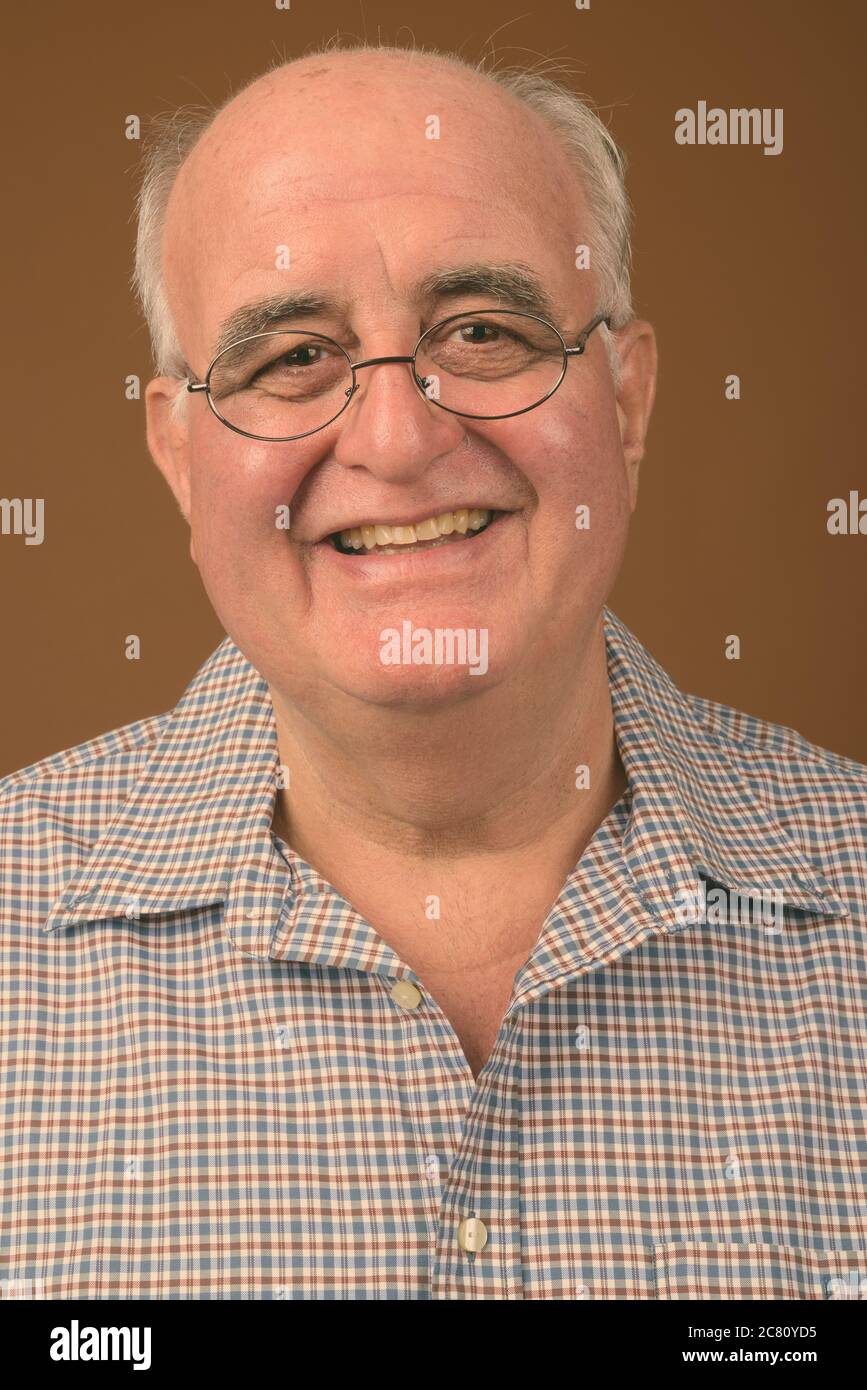Overweight senior man wearing eyeglasses against brown background Stock ...