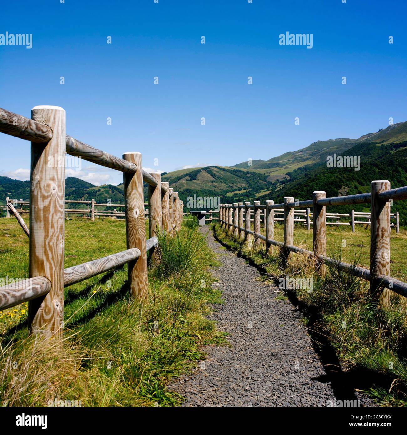 Scenic pathway lined with rustic wooden fences in a mountainous region ...