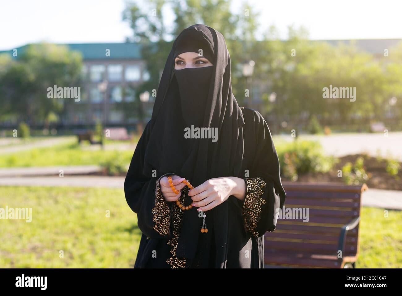 A woman from the east in national Islamic clothes holds religious ...