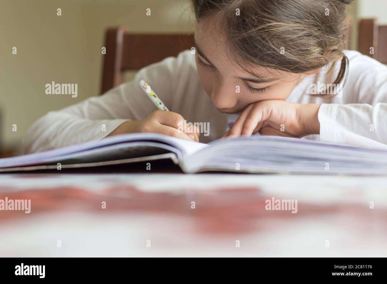 Elementary student makes her homework. She makes her own homework alone ...