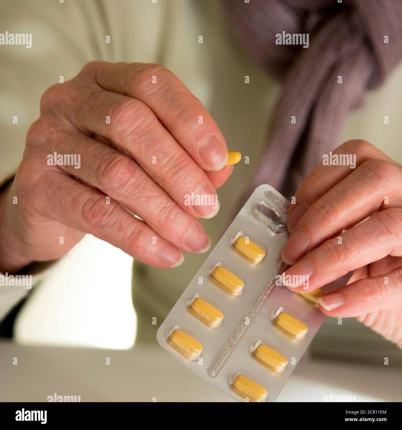 Senior person taking medication from a blister pack at home during ...