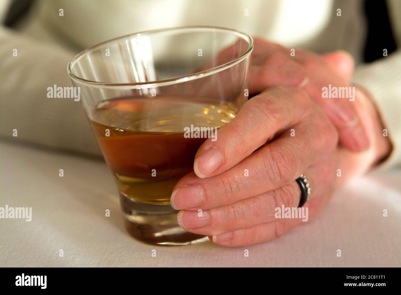 Whiskey glass in hands with a ring on the finger during a quiet moment ...