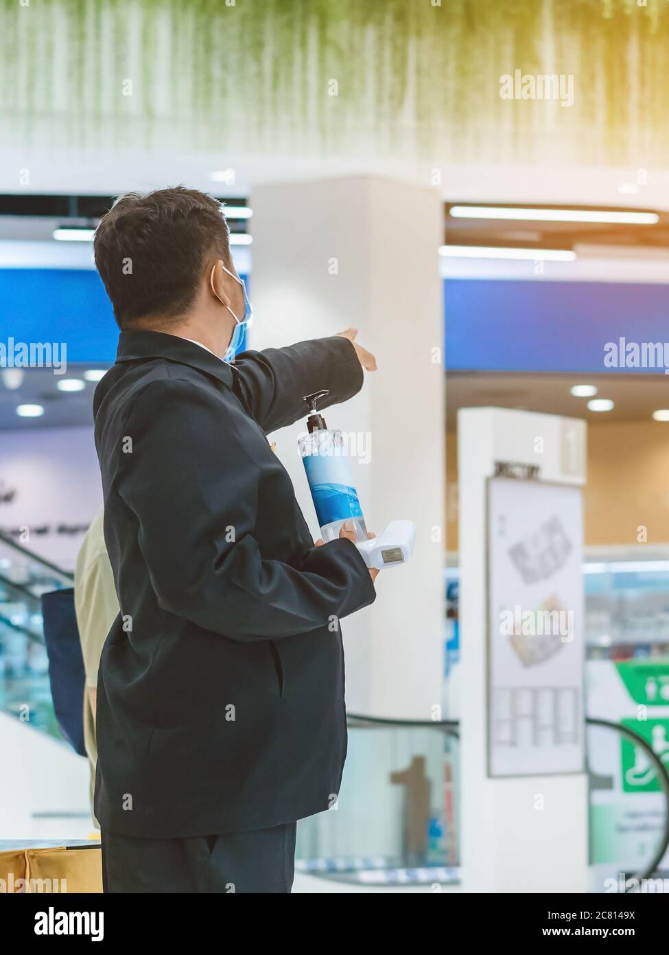 A male security guard wear face mask points out a way for customers to ...