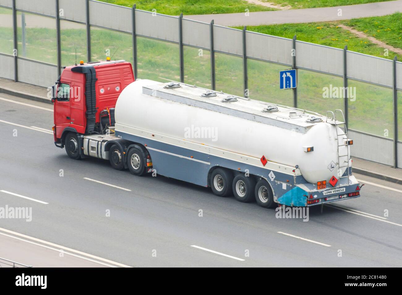 Heavy truck with a tank for flammable liquids rides on the road, back ...