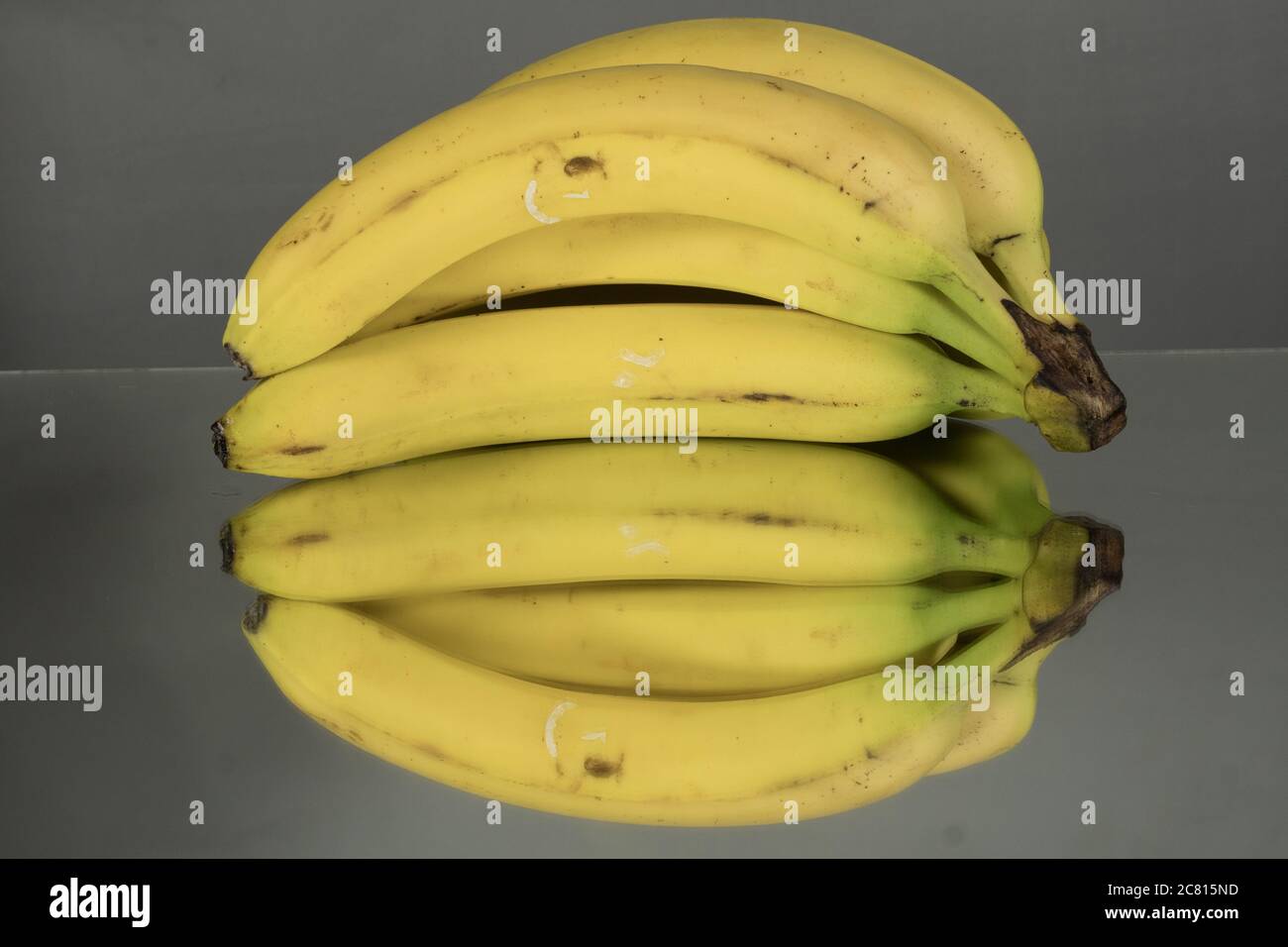 A bunch of bananas on mirroring table on mirror red background with ...