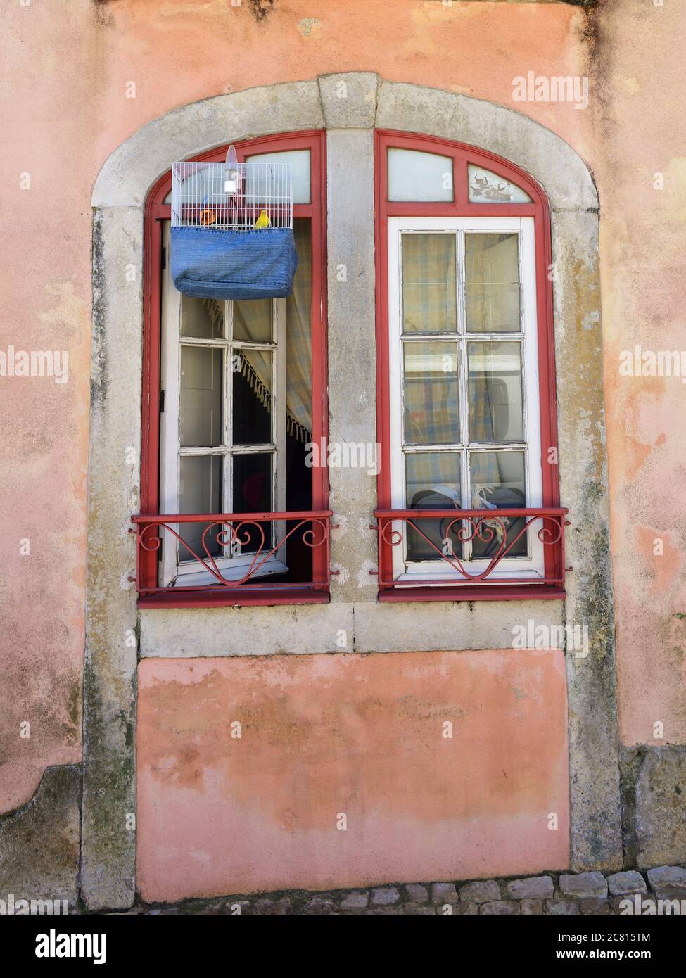 Old plastered facade of house with open window and cage with canary ...