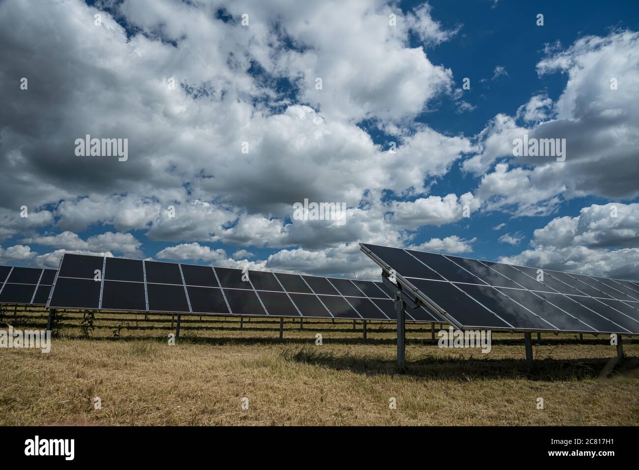 Solar panels in the grain field in the countryside under the cloudy sky ...