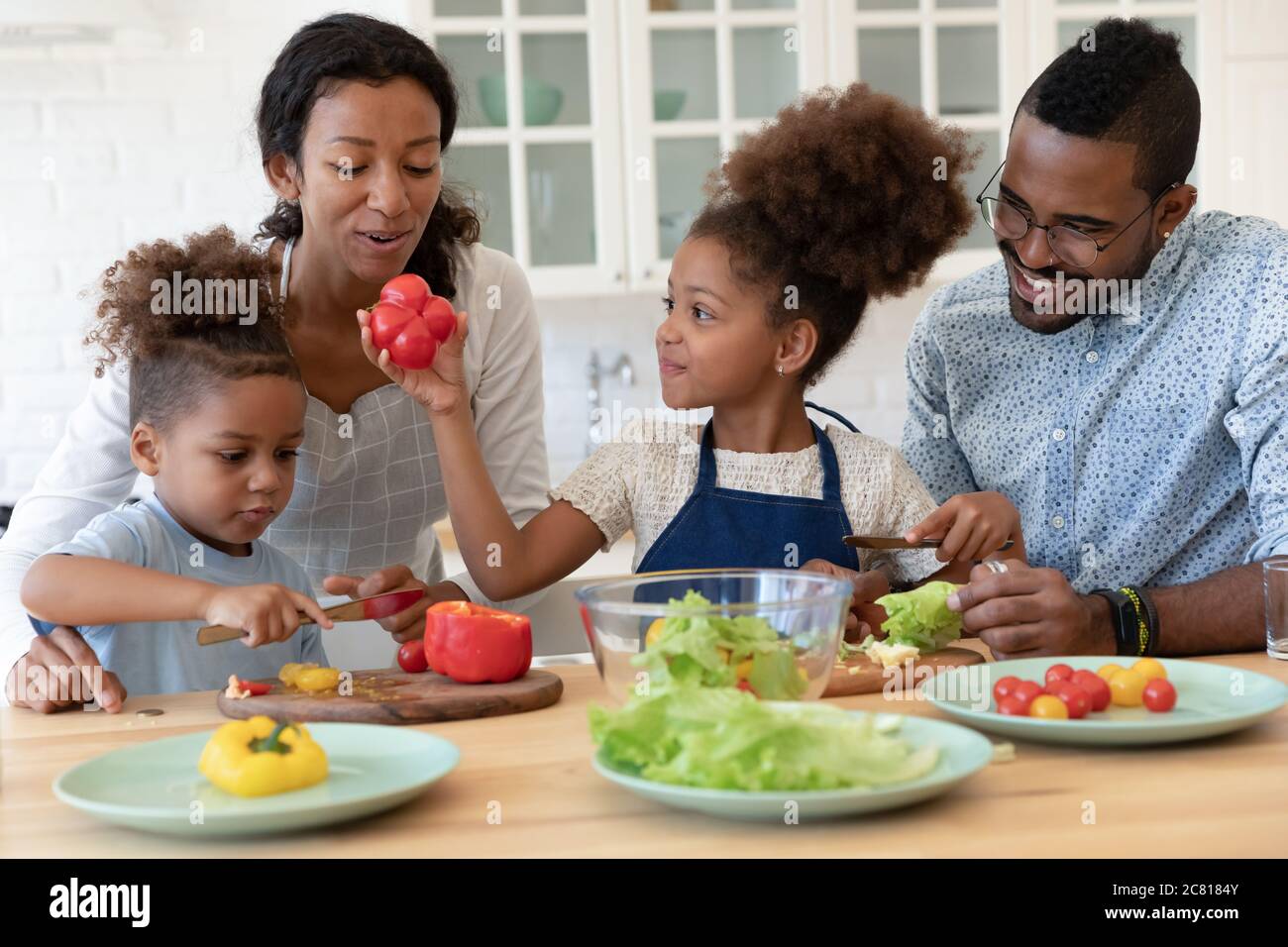 Happy young biracial family with kids cooking together Stock Photo - Alamy