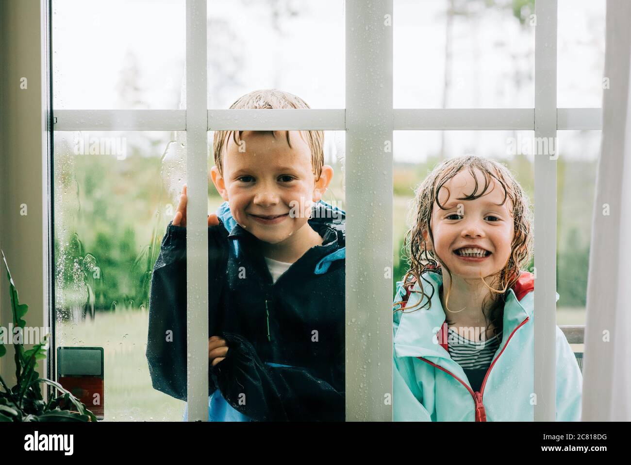 brother and sister stood looking through a window whilst playing Stock ...