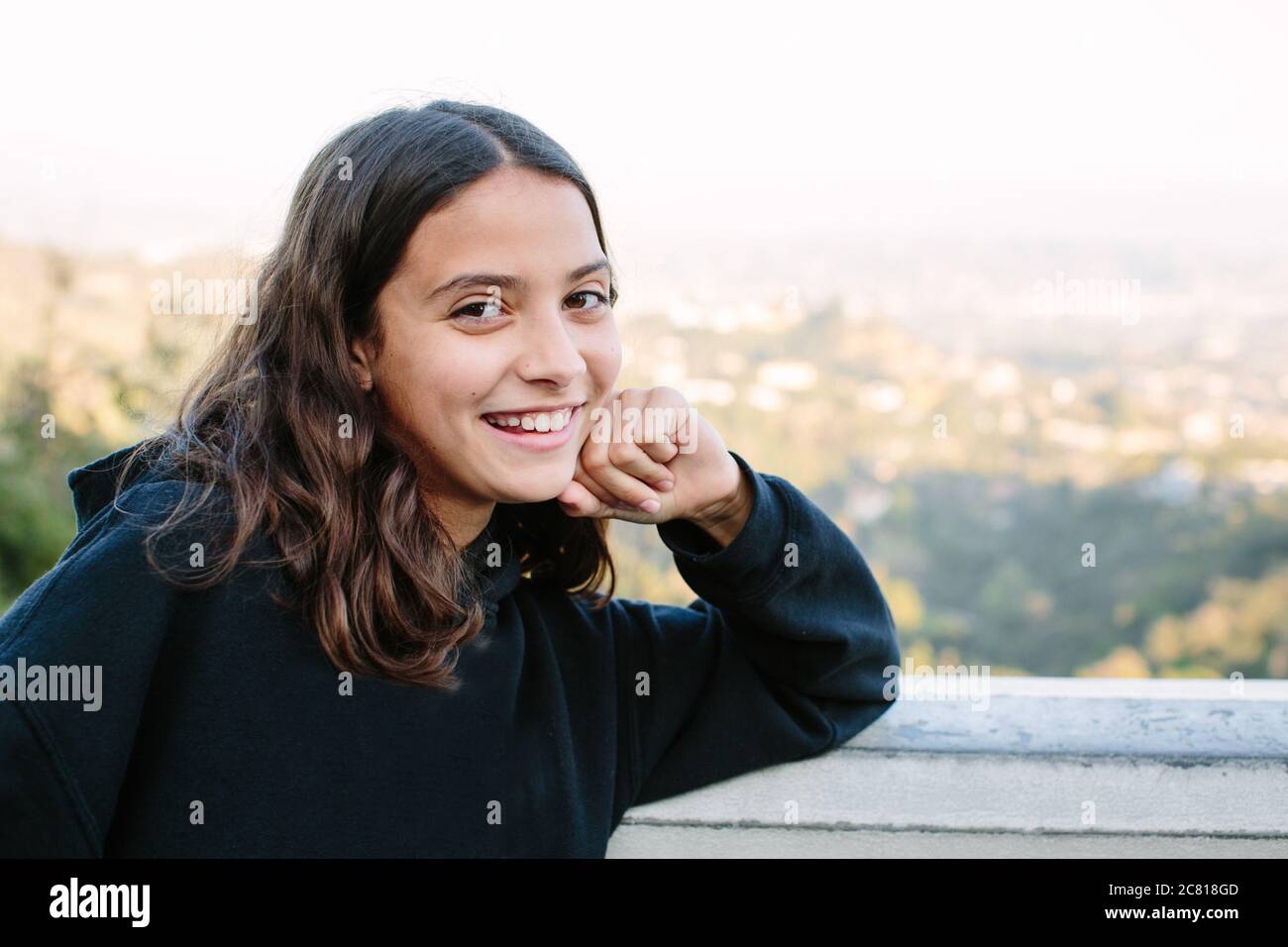 Twelve year old girl smiles for a cheesy portrait at a scenic overlook ...