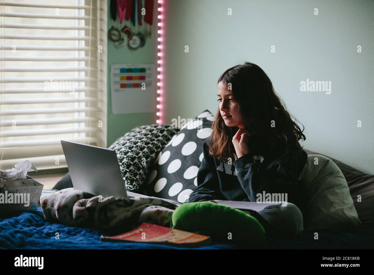 Tween girl looking at her laptop screen during a zoom class meeting ...