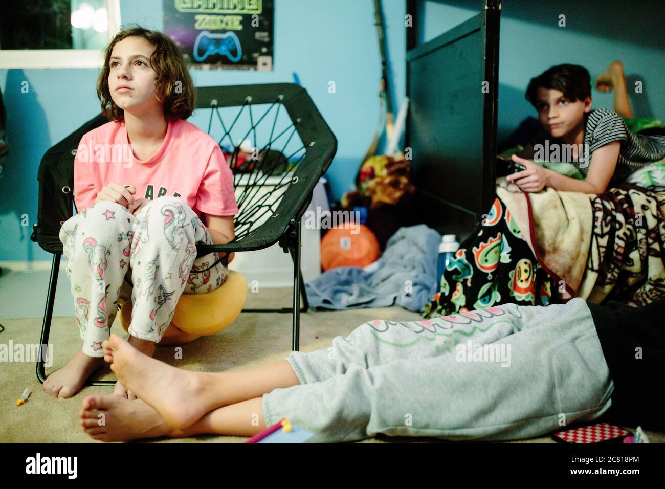 Kids relax in a bedroom watching brother play video game Stock Photo ...