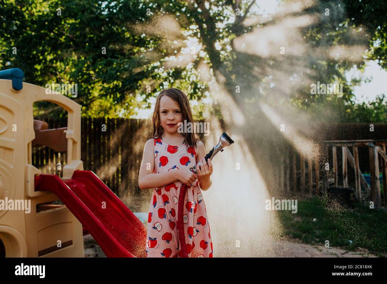 Young girl spraying mist from garden hose in backyard Stock Photo - Alamy