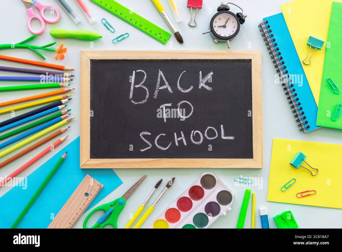 School supplies stationery, colour pencils, paints, alarm clock on ...