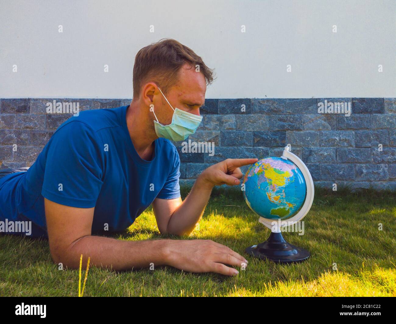 Man wearing Face Mask holding the Earth globe world map in hand ...