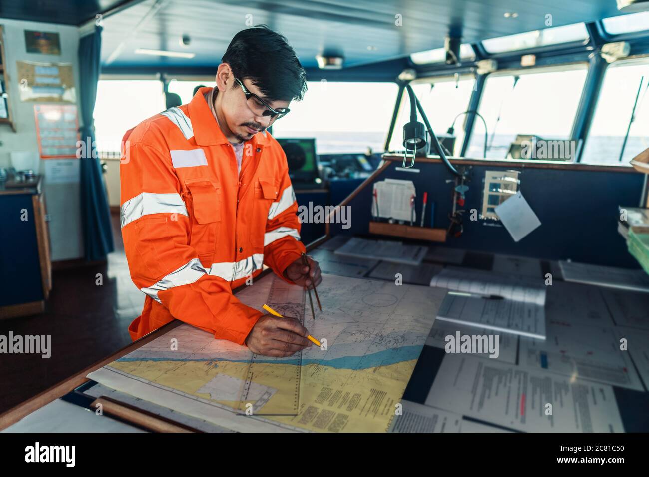 Filipino deck Officer on bridge of vessel or ship. He is plotting ...