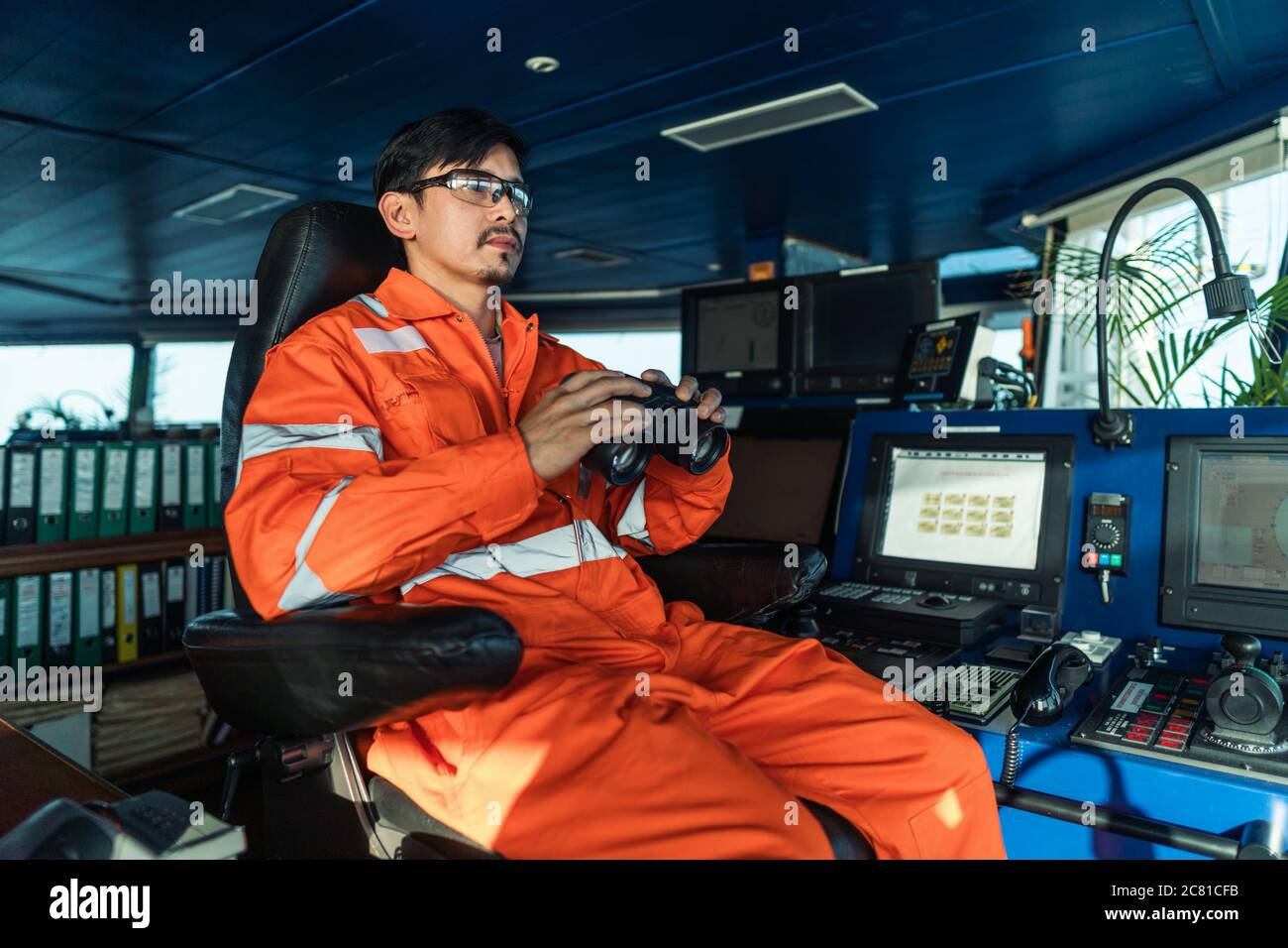 Filipino deck Officer on bridge of vessel or ship looking through ...