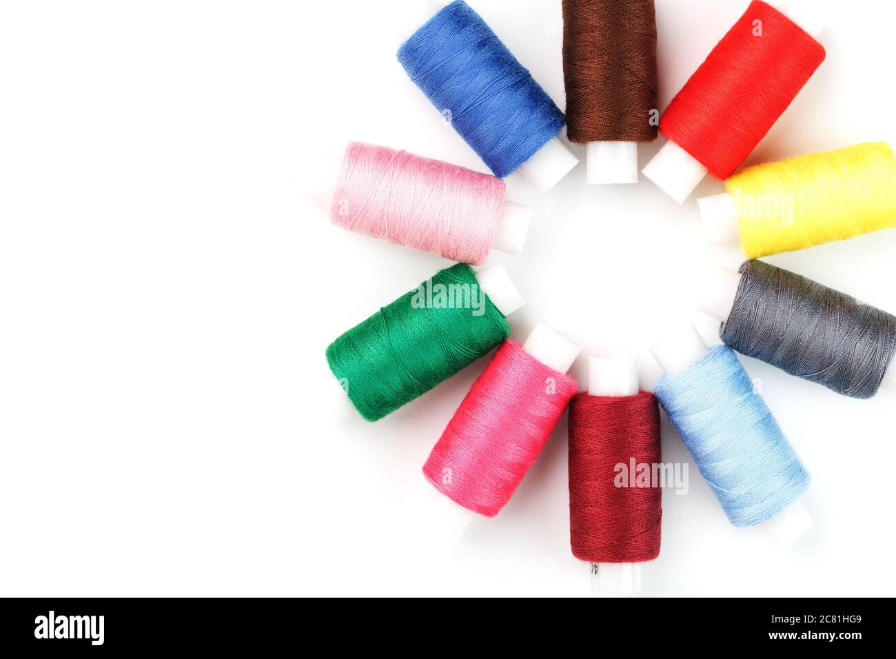 Sewing threads of different colors on reels on a white background in a ...