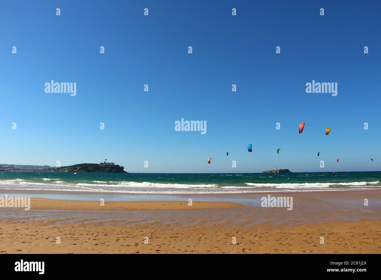 Kitesurfing or kiteboarding from the beach of Somo on a sunny windy ...