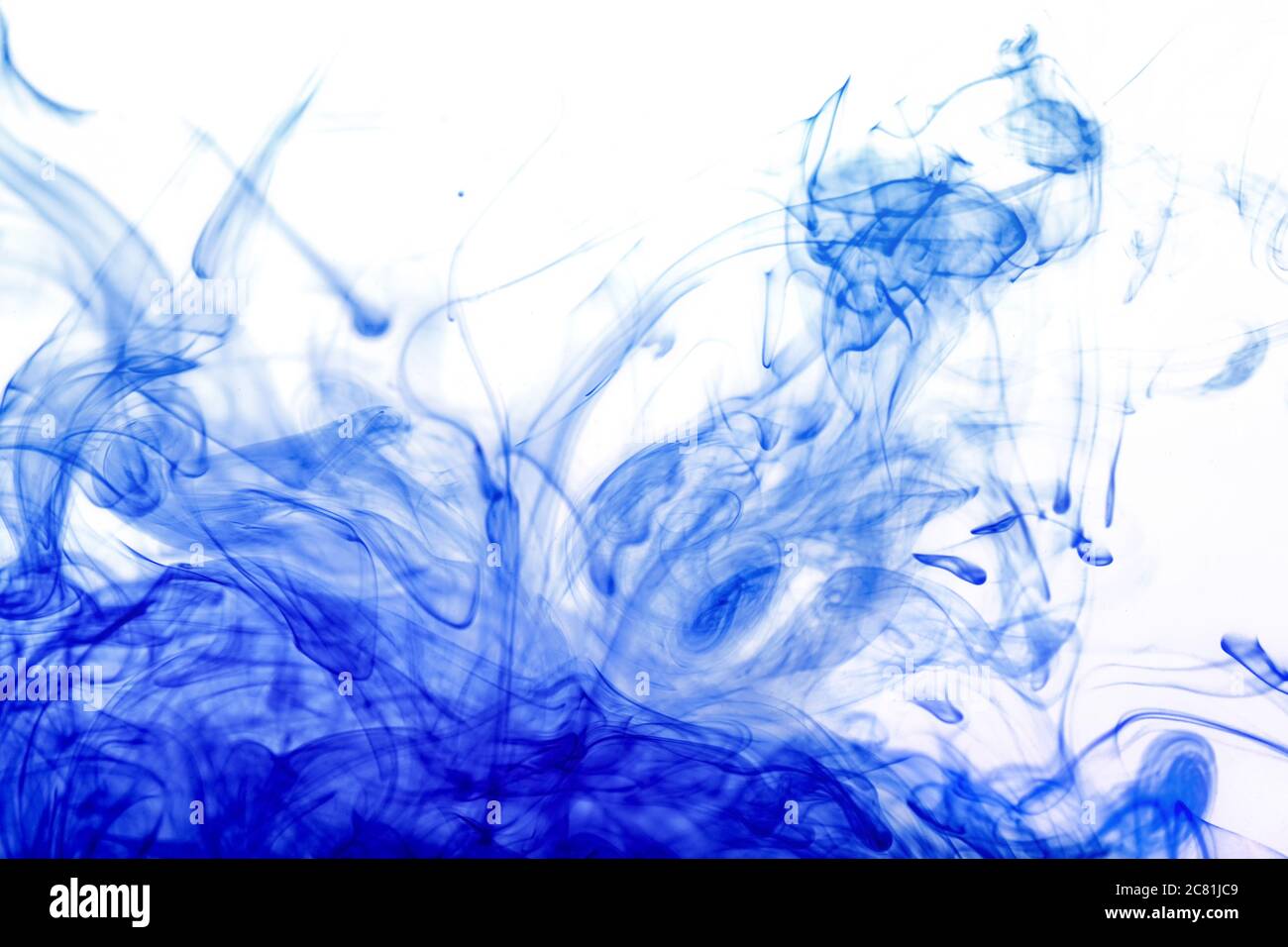 Blue ink injected from syringe, colour mixing with water creating ...