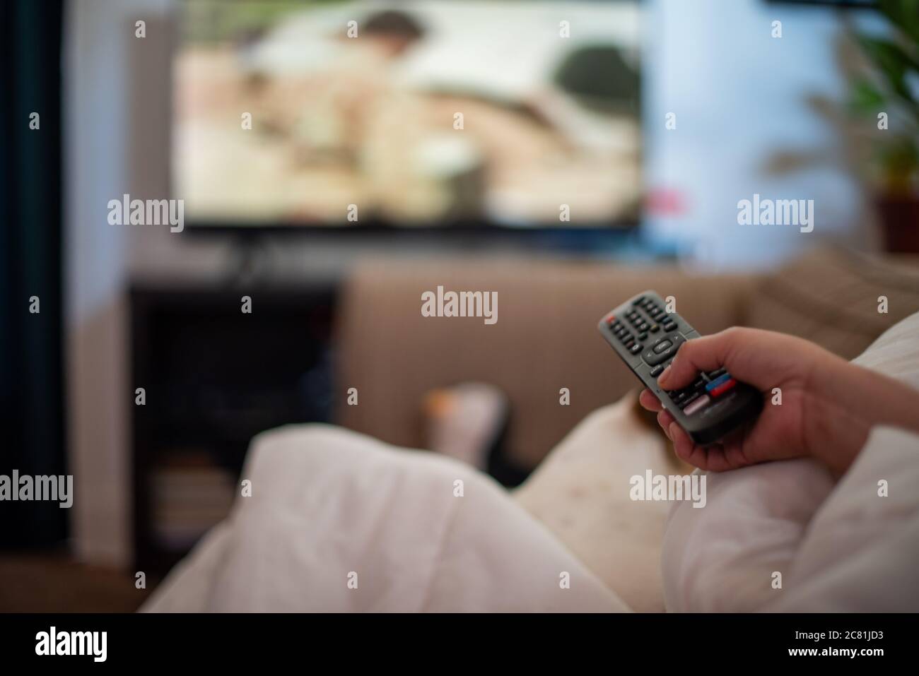 Rear view of person holding remote control in hand Stock Photo - Alamy