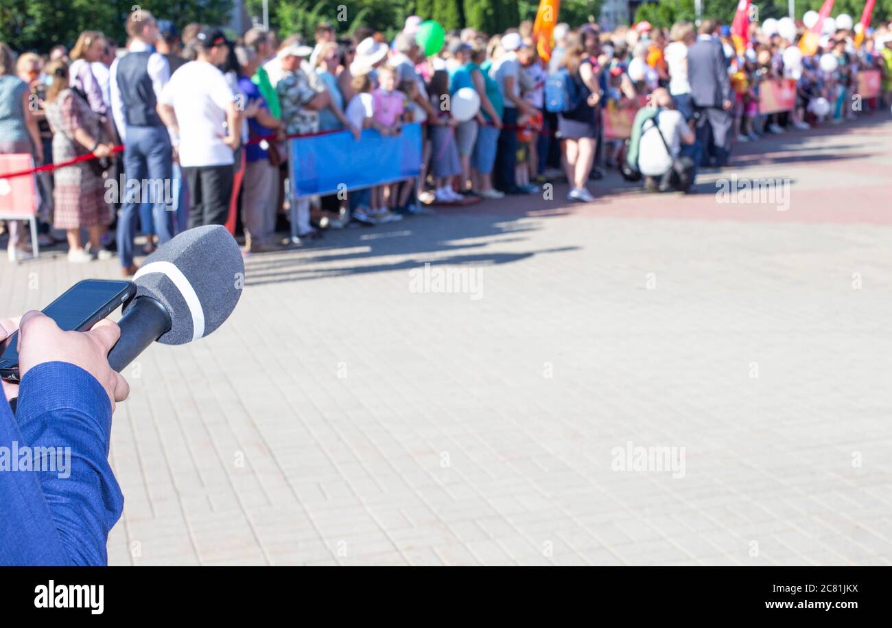 hands of a reporter with a microphone on the background of a crowd of ...