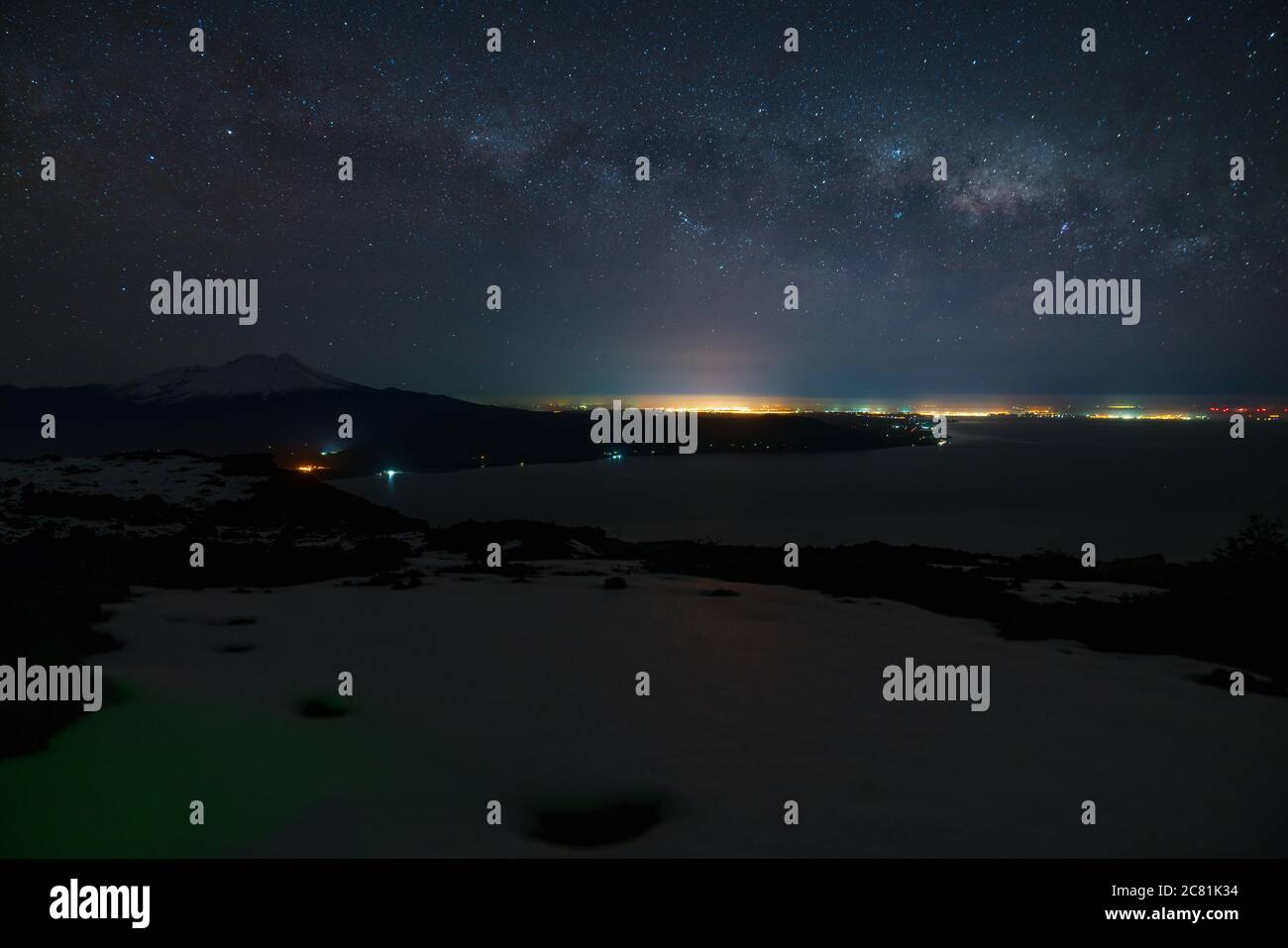 night sky with the milky way over the llanquihue lake, city lights and ...