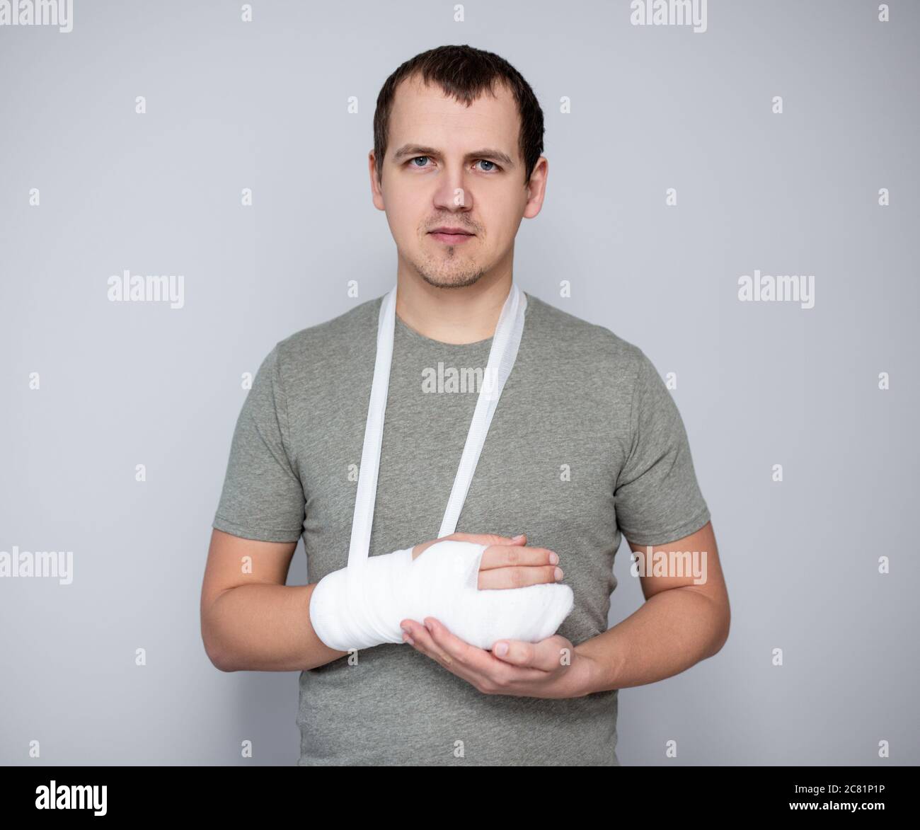 first aid concept - young man with bandage and gypsum on his hand over ...