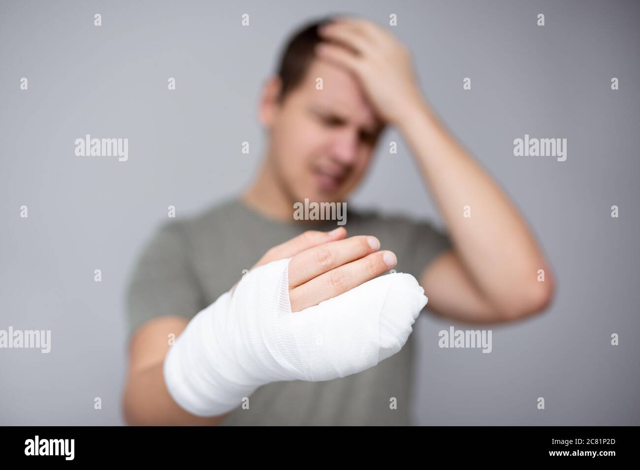 injury and first aid concept - unhappy man with broken hand in bandage ...
