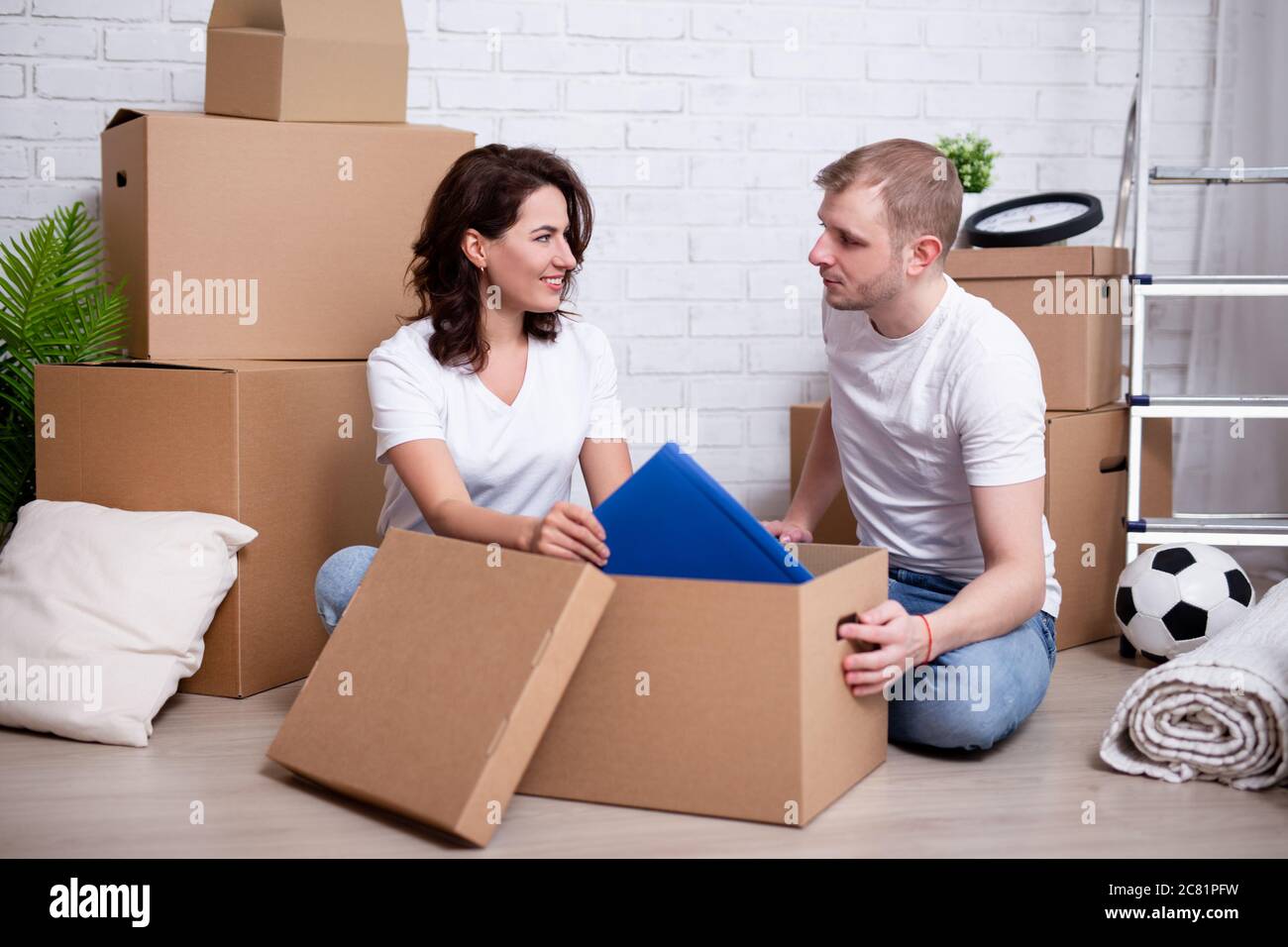 Happy Young Couple Packing Cardboard Boxes To Move In New House Stock