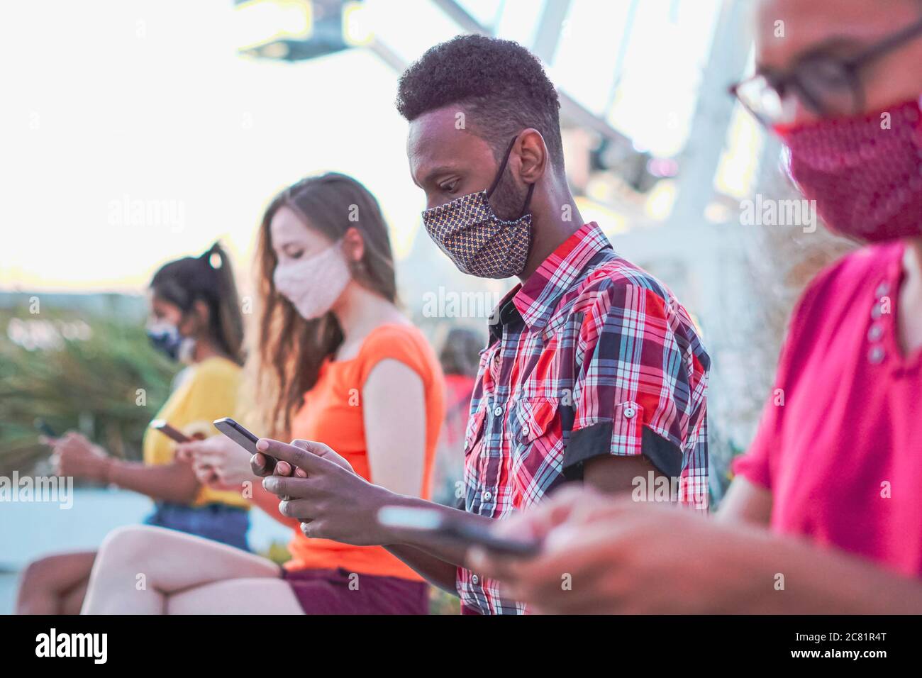 Friends using their smartphones in covid 19 times protected with face ...
