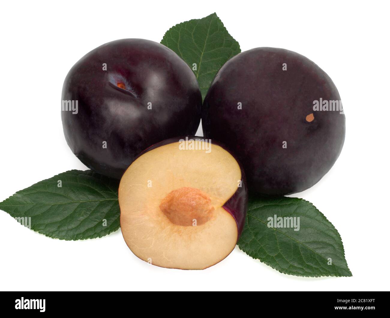Three plums with plum leaves on white background Stock Photo - Alamy