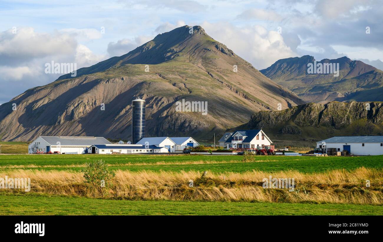 Barns, silo and farm house with peaked mountains in the background ...