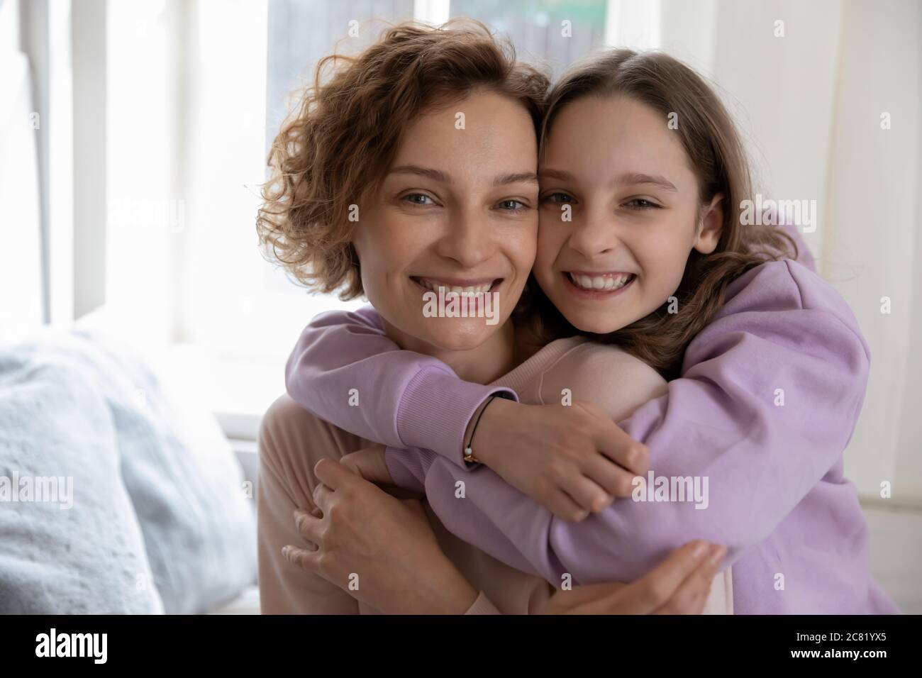 Head shot portrait smiling teenage daughter hugging mother from back ... Head shot portrait smiling teenage daughter hugging mother from back ...