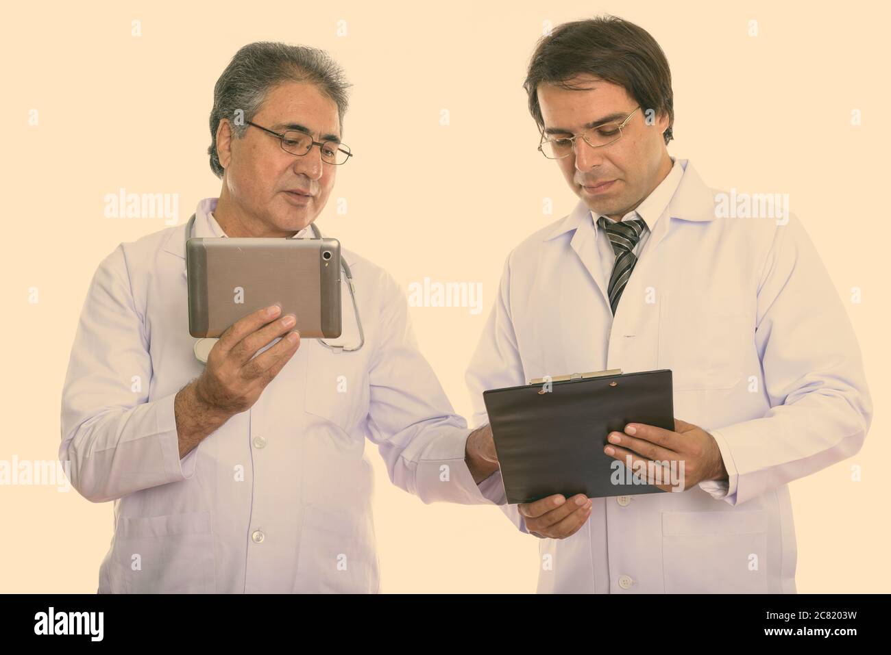 Studio shot of young and senior Persian man doctor holding digital ...
