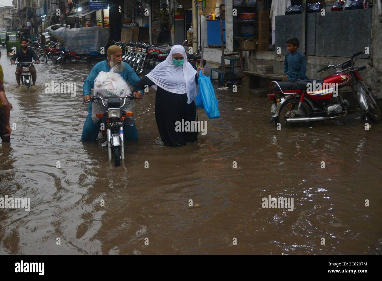 Lahore, Pakistan. 20th July, 2020. Pakistani commuters wade through a ...