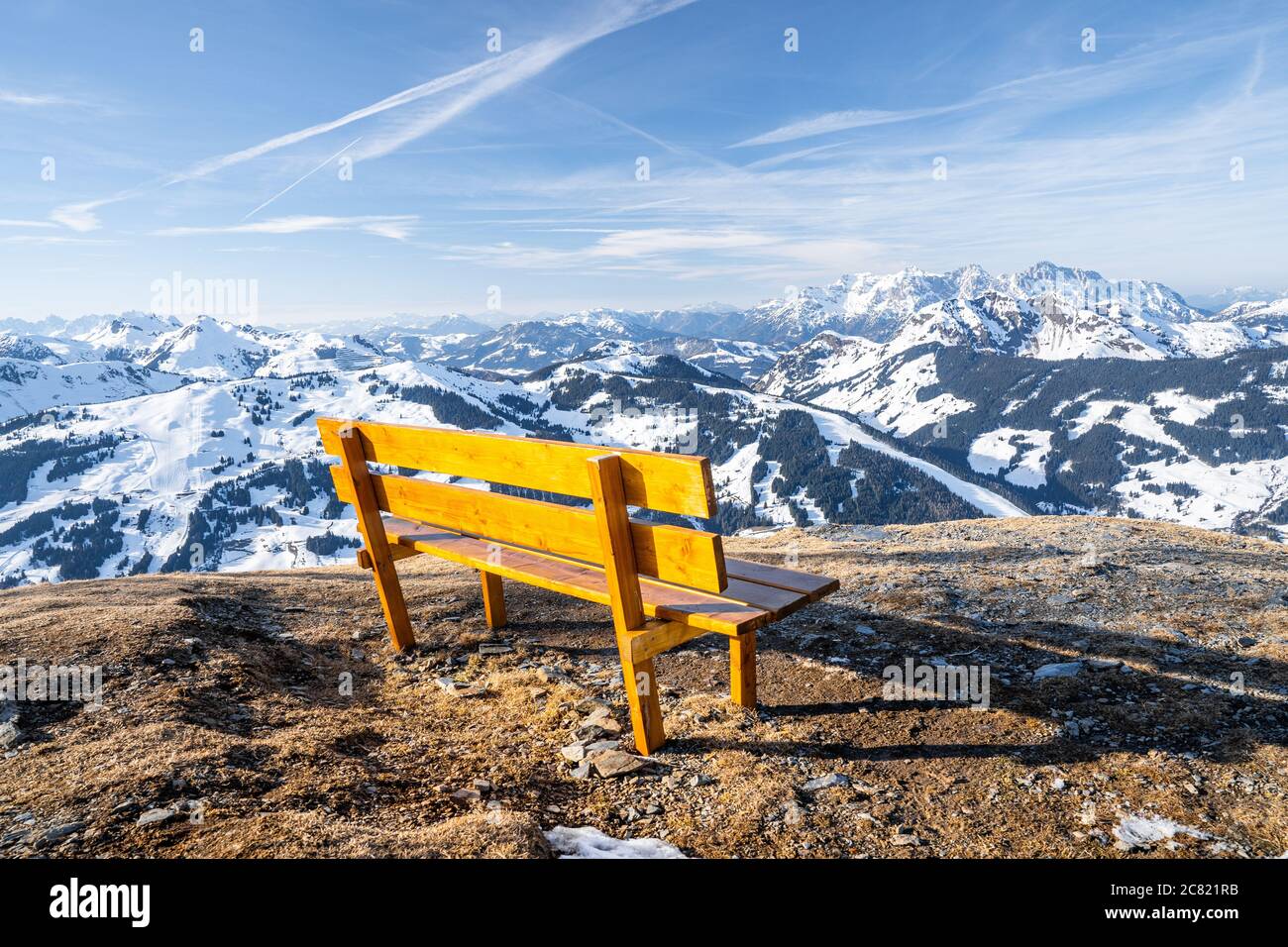 Yellow bench on a mountain peak with a view of the snow-covered Alps ...