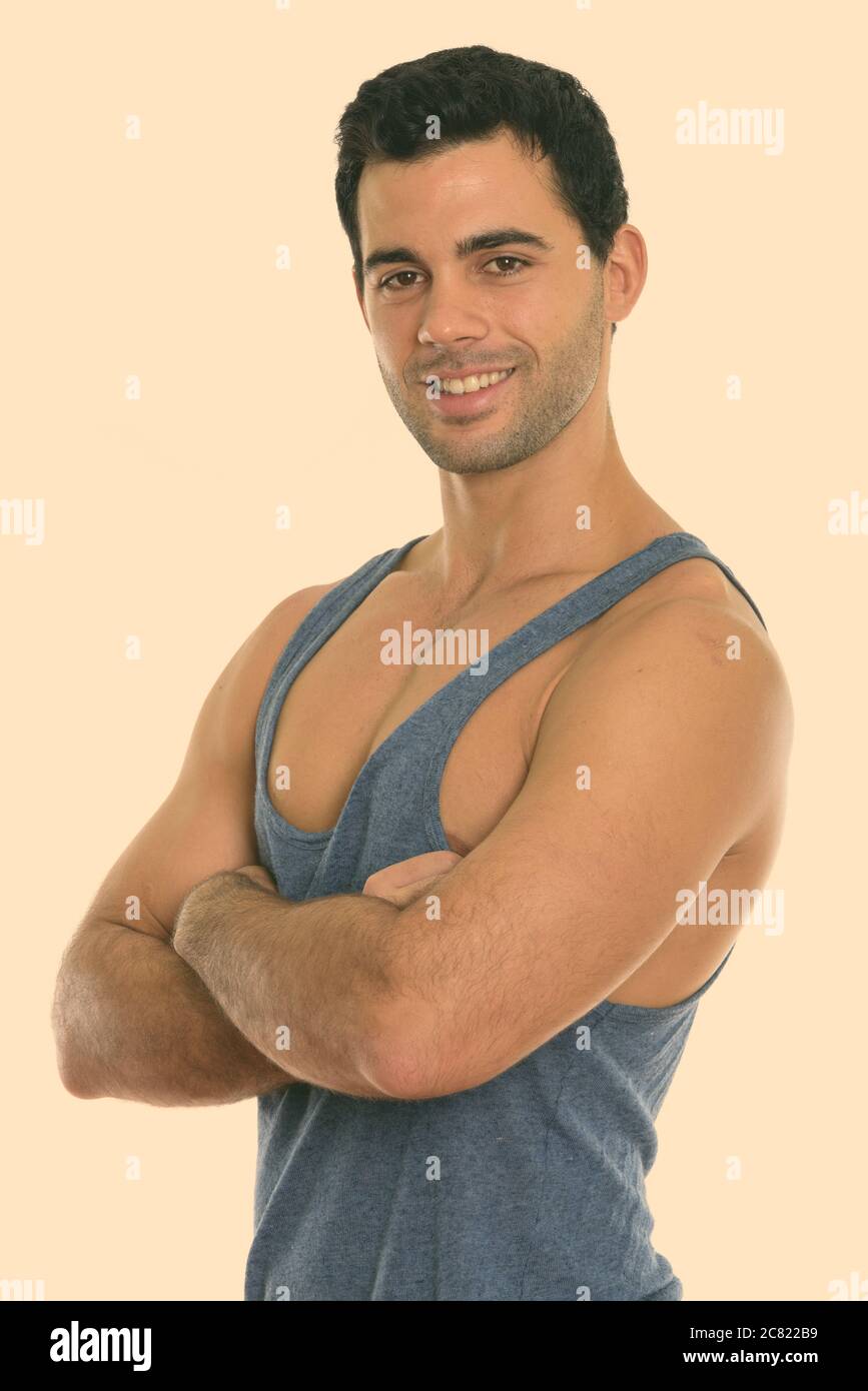 Studio shot of young happy handsome Hispanic man smiling with arms ...
