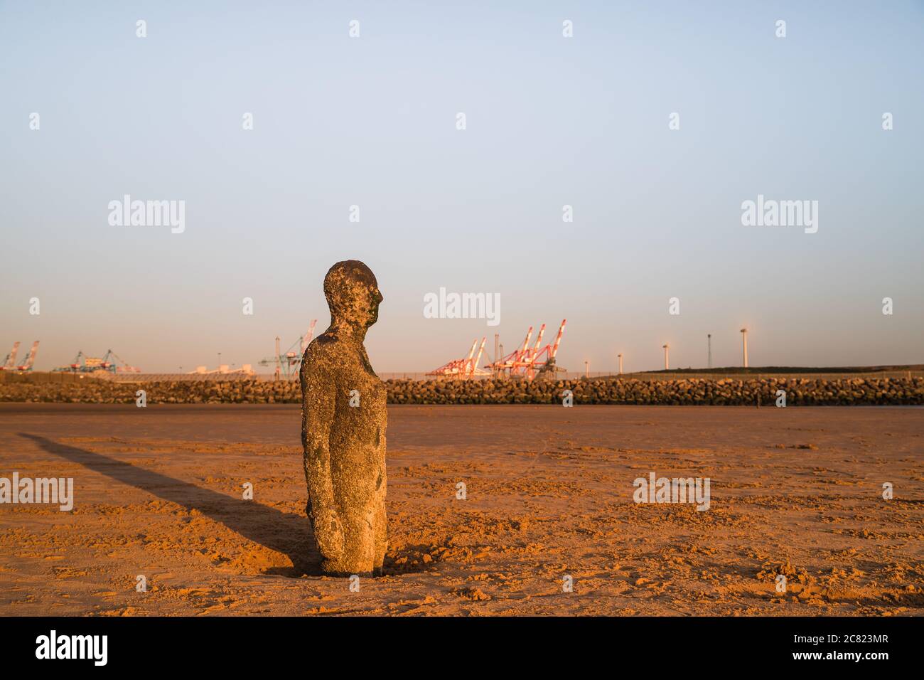 Iron Man statue up to his thighs in sand seen on the beach at Crosby ...