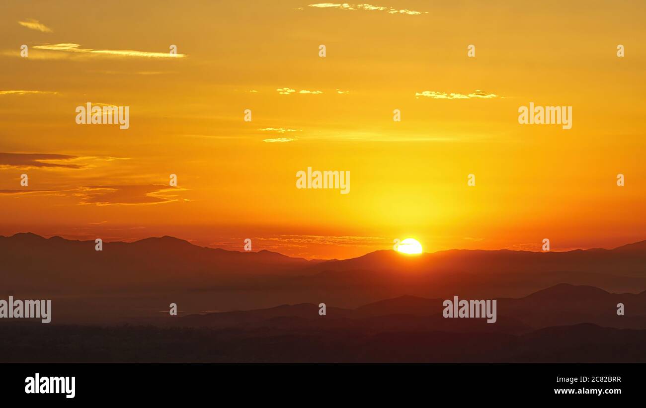 Sun rising over mountains on the horizon Stock Photo - Alamy