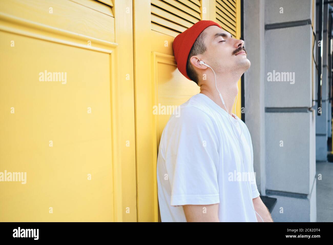 Side view of young attractive mustache man in T-shirt and red hat ...
