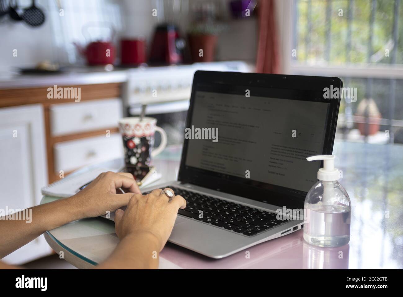 Black computer, a plastic bottle of sanitizer and a cup on the table ...