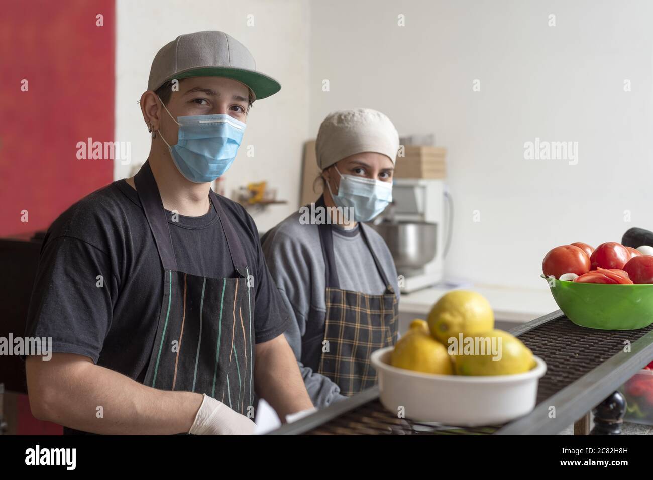 Hispanic chefs cooking in the kitchen wearing protective medical face ...